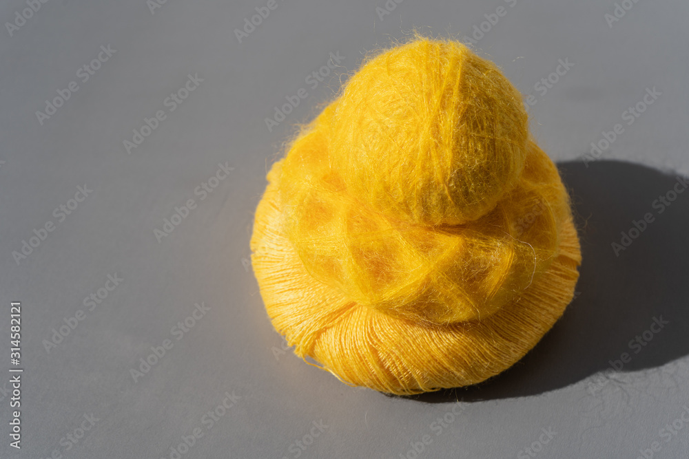 Pyramid of skeins of yellow yarn from alpaca wool on a gray table. Side ...