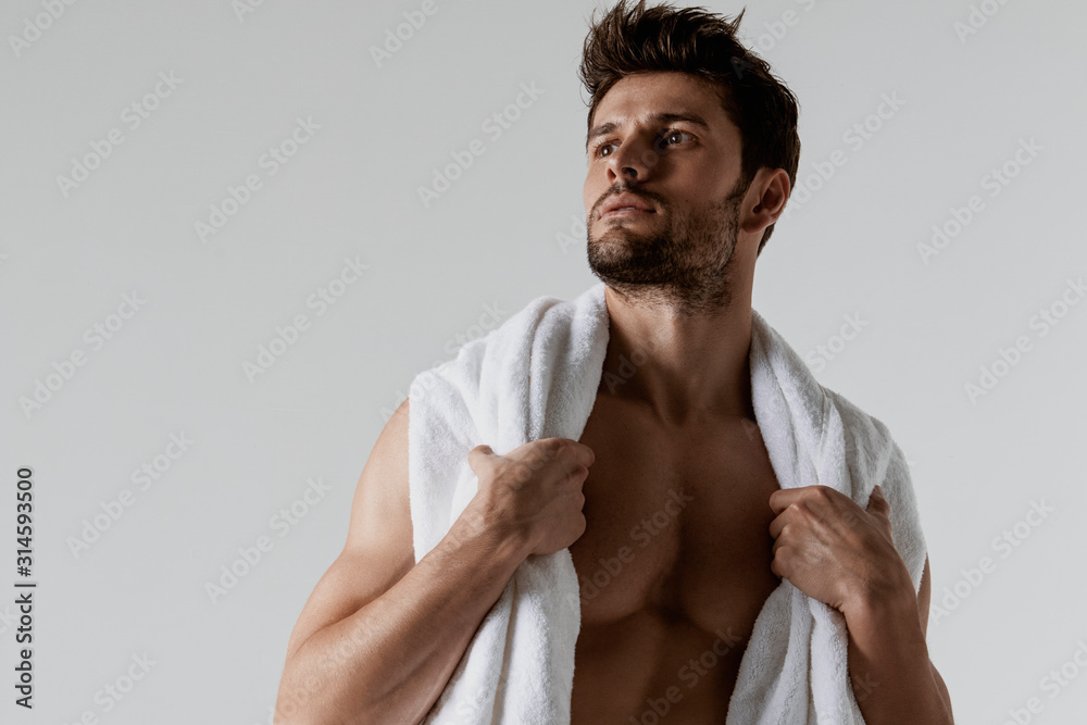 Sexy sport muscle strongface guy with white towel on grey isolated font ...