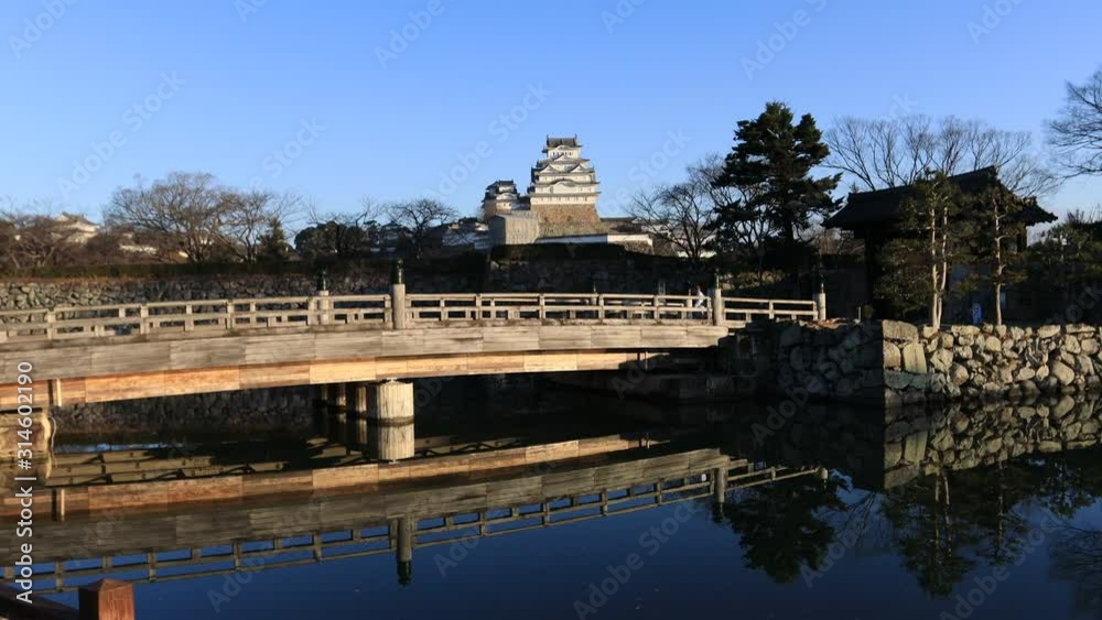 Wooden bridge over water filled moat around white castle near Osaka in ...