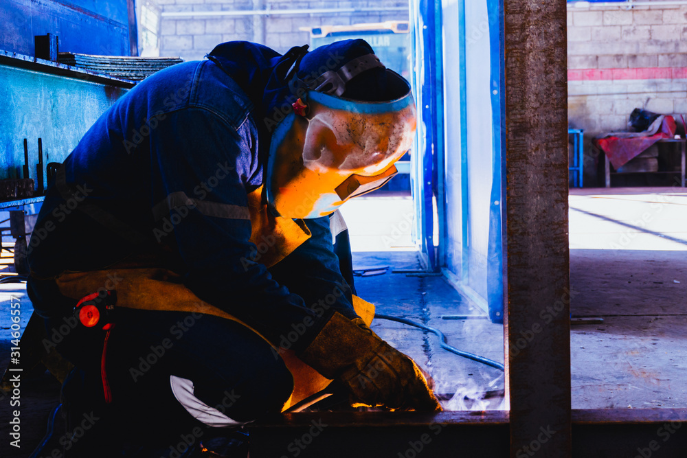 Hombre soldador hincado trabaja soldando metal Stock Photo | Adobe Stock