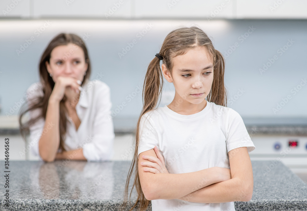 Sad girl and her mother stand at home after they quarreled. Family ...