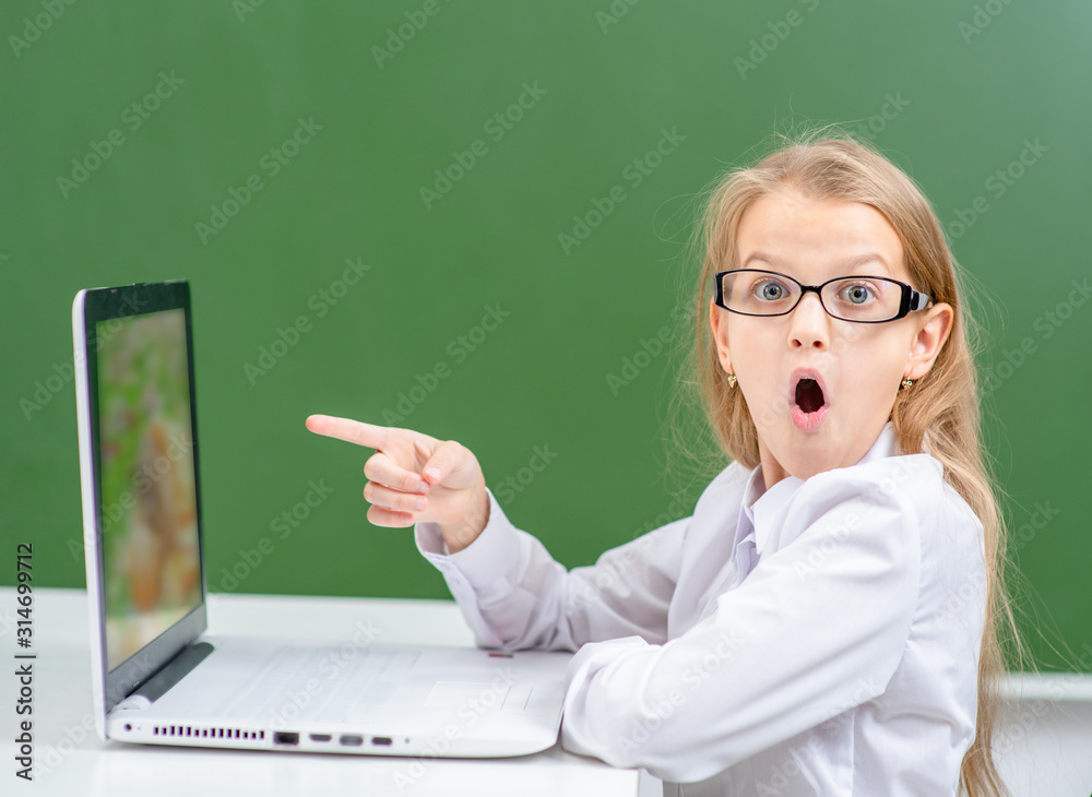 Shocked girl points on screen of the laptop. Internet safety concept ...