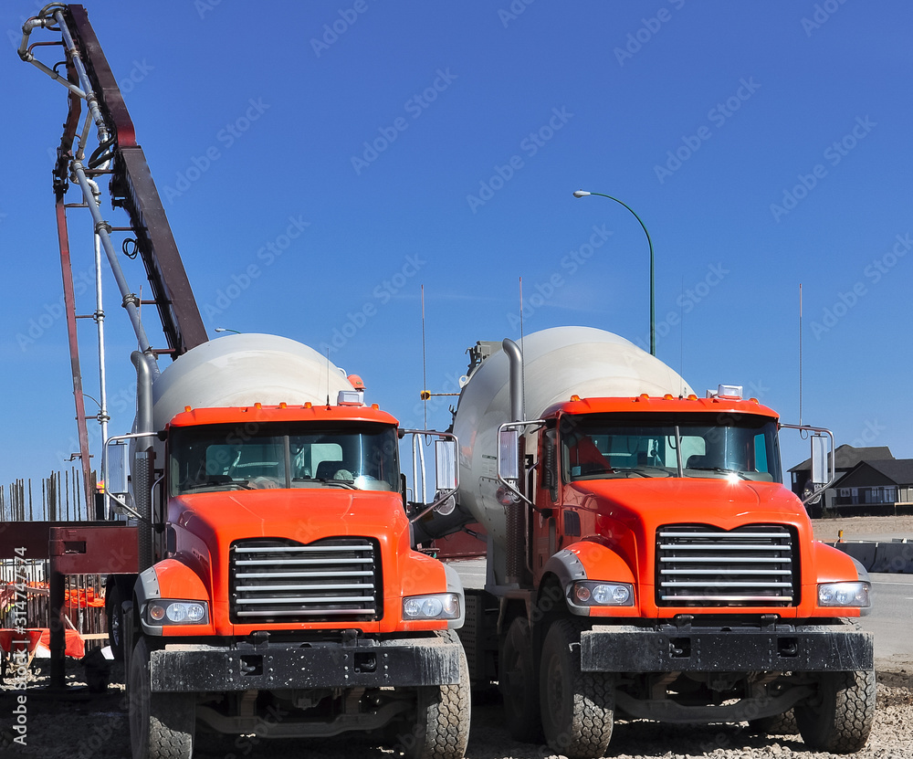 Concrete trucks discharginging their loads of concrete into an ...