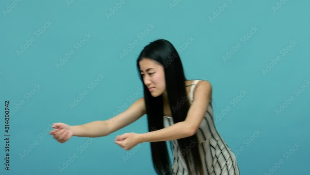 Young asian woman with long black hair in dress pulling heavy invisible ...