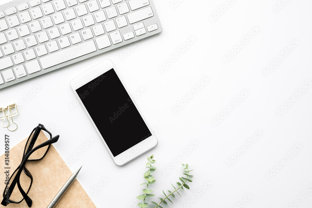 Smartphone with blank screen is on top of white office desk table with ...