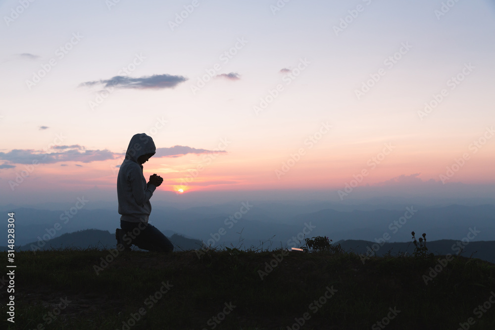A women is praying to God on the mountain. Praying hands with faith in ...