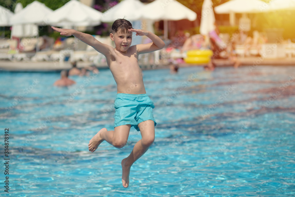 Caucasian boy having fun making high jump to plunge into swimming pool ...
