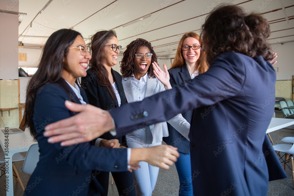 Team leader hugging her happy younger colleagues. Smiling business team ...