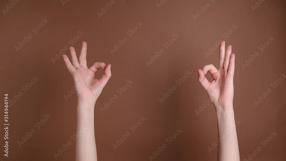 Closeup side view of unrecognizable female shows an ok sign with both ...