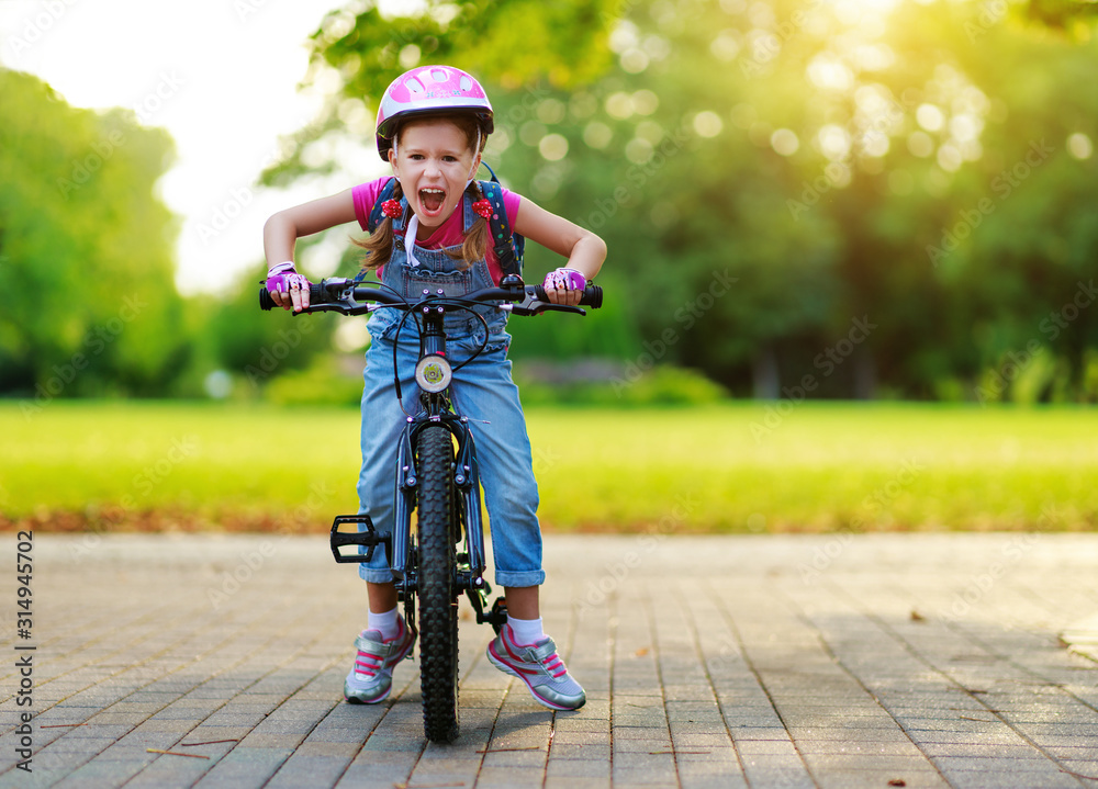 happy cheerful child girl riding a bike in Park in nature. Stock Photo ...