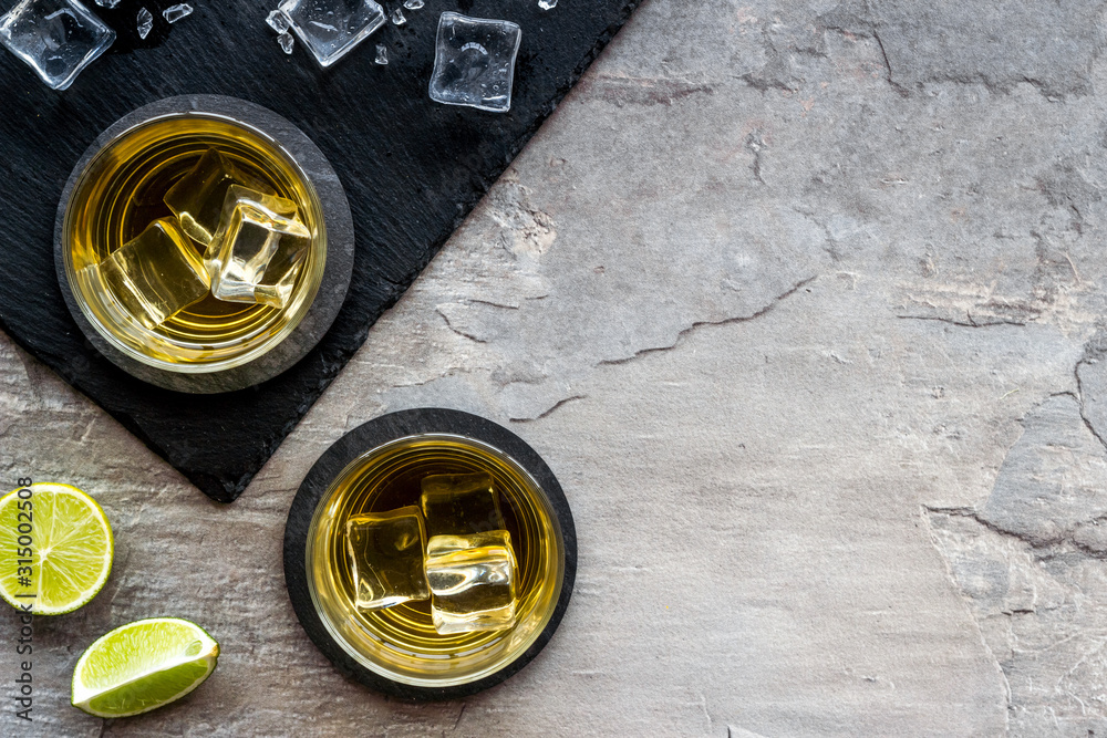 Bar background with whiskey and ice on grey stone desk top-down frame ...