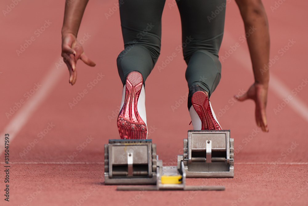Back view of female feet on starting block ready for a sprint start ...
