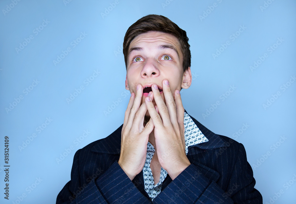 Horrified young man man covering mouth with hands looking at camera ...
