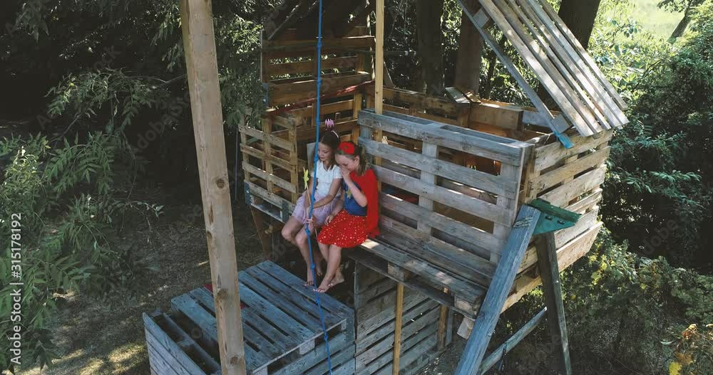 Girls wearing superhero disguises, sitting on treehouse Stock Video ...