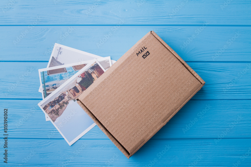 Flat lay, carton sending mail package and vacation photos. Top view ...
