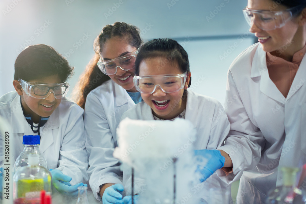 Curious, smiling students watching chemical reaction, conducting ...