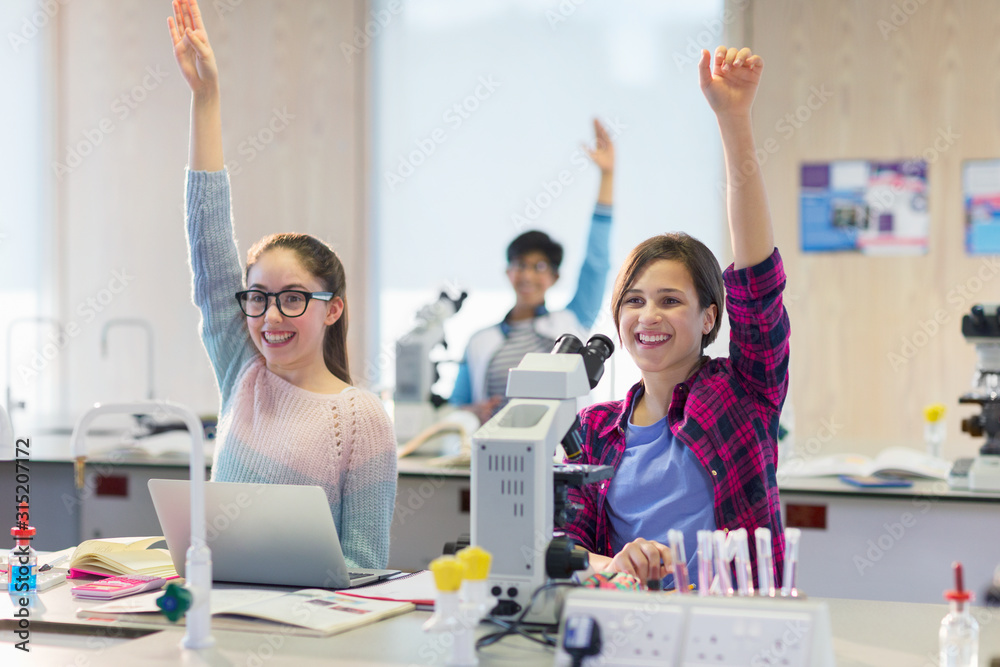 Eager, smiling students raising hands in science laboratory classroom ...