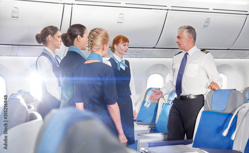 Pilot and flight attendants talking, preparing on airplane Stock Photo ...