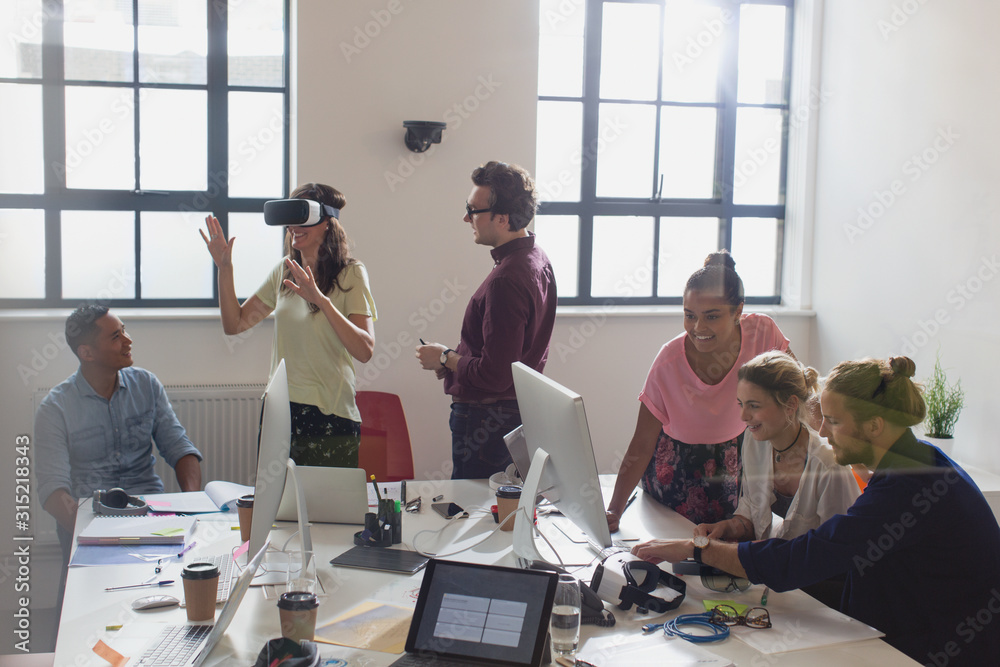 Foto de Computer programmers programming virtual reality simulator glasses in open plan office ...