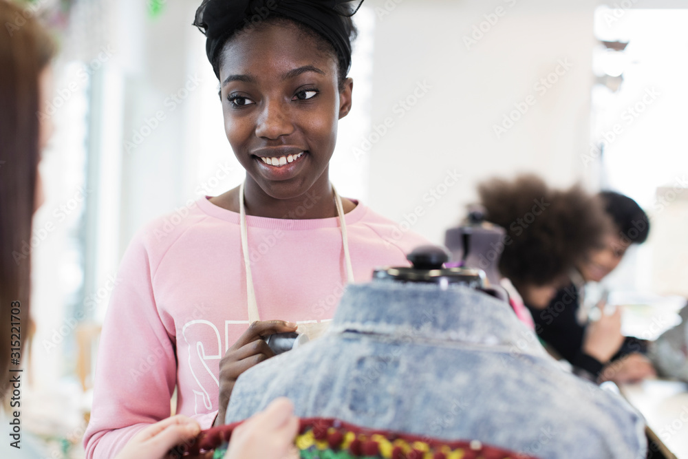Smiling teenage girl designing denim jacket in fashion design class ...