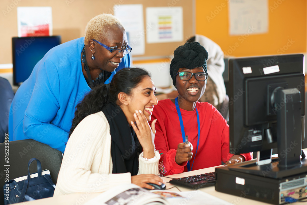 Female professor and college students using computer in computer lab ...