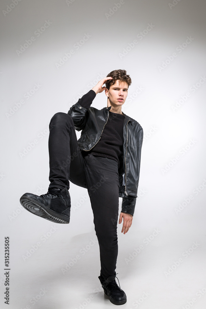 full length portrait of young fit man in dark cloths on the white ...