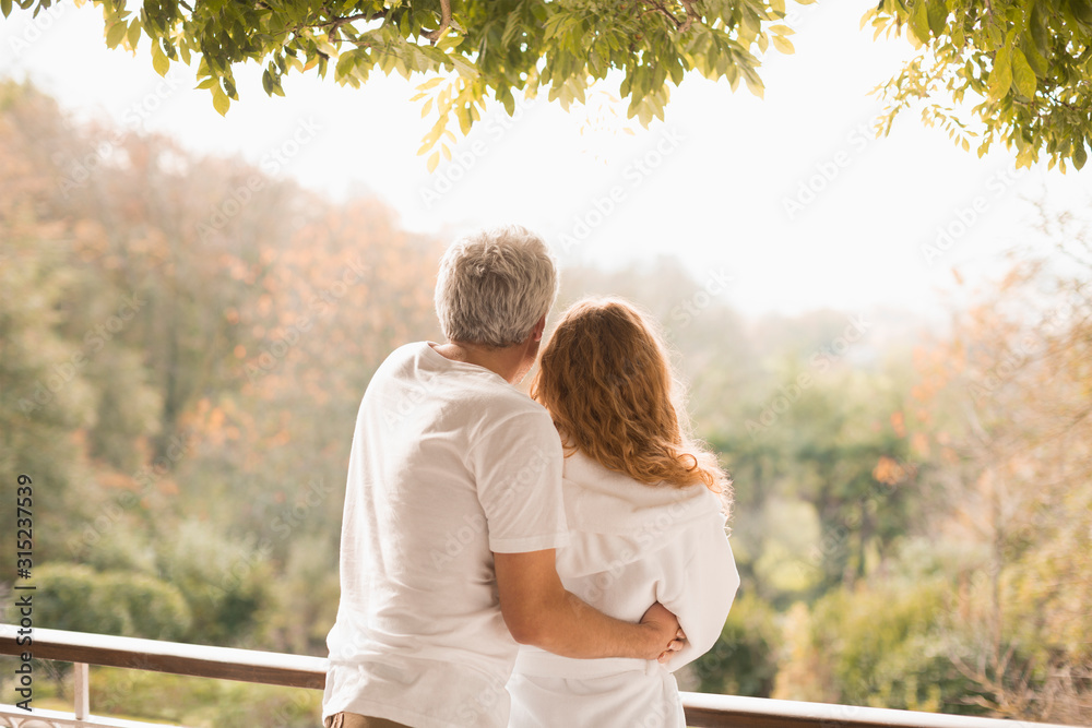 Affectionate couple hugging looking at autumn trees on patio Stock ...