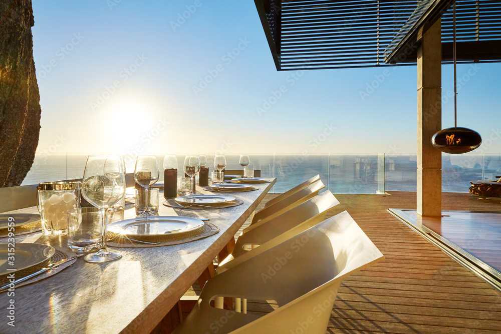 Sun shining over ocean behind luxury patio dining table with ...