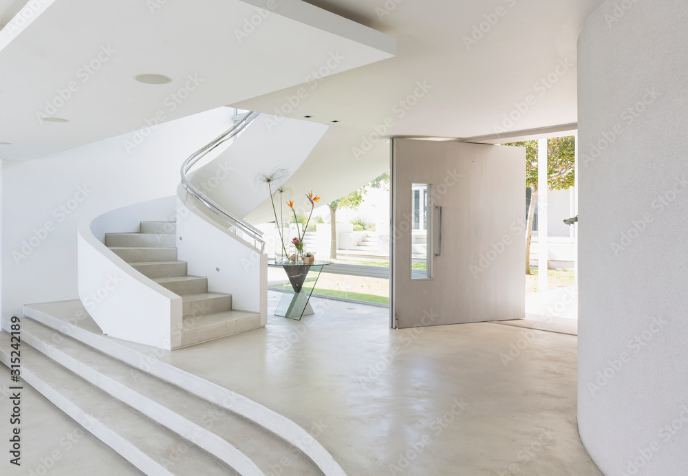 White foyer and spiral staircase in modern luxury home showcase ...