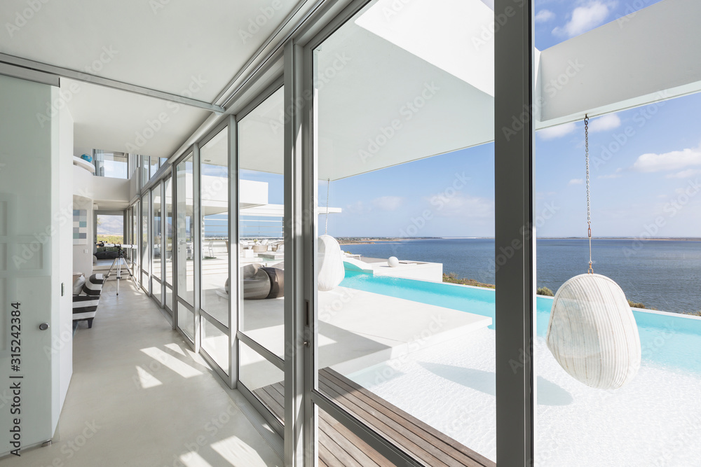 Modern luxury home showcase windows with infinity pool and ocean view ...