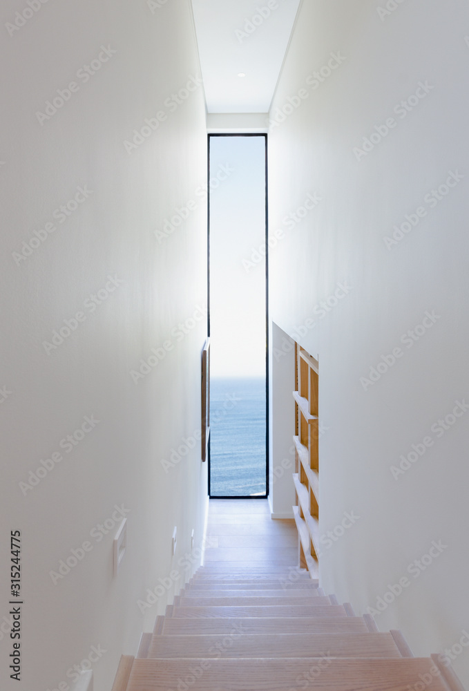 Stairwell facing long window with ocean view in modern, luxury home ...