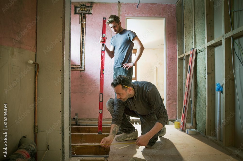 Construction workers using tape measure and level tool in house Stock ...