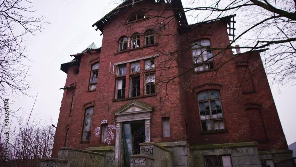 the creepy abandoned hotel made of red bricks with broken windows ...