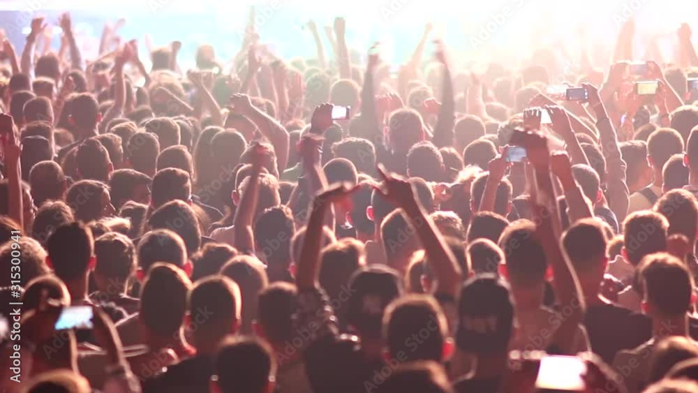 Fans waving their hands and filming by phones crowd at a concert ...