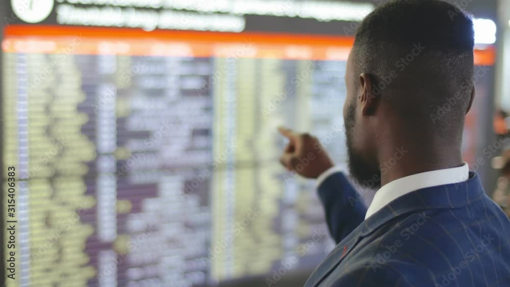 African businessman checking his flight boarding time at information ...