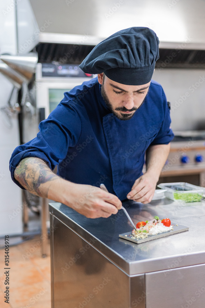Concentrated professional male chef garnishing and finishing delicious ...