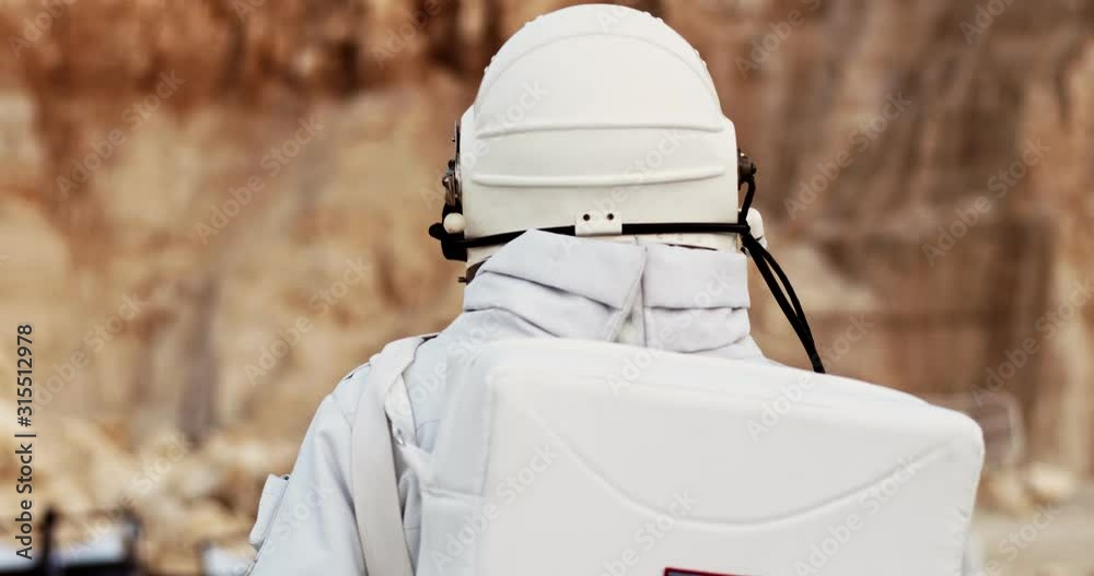 Rear of the spaceman in the white space costume with head armor walking ...