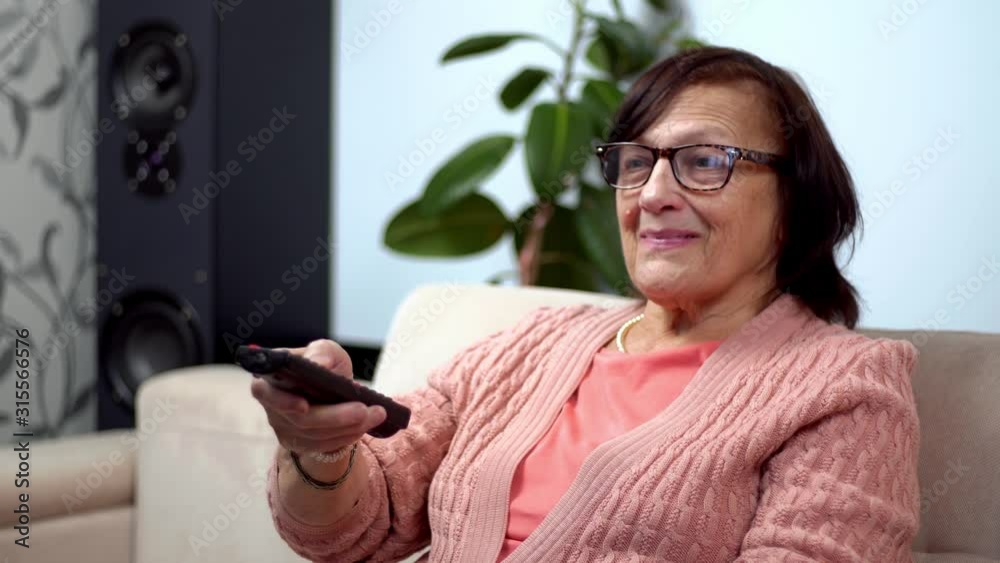 Grandmother With TV Remote Watching TV And Channel Surfing. Senior ...