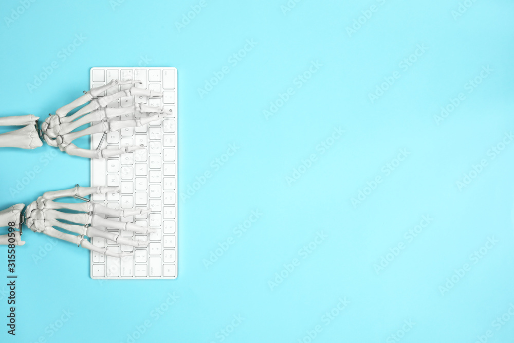 Human skeleton using computer keyboard on light blue background, top ...