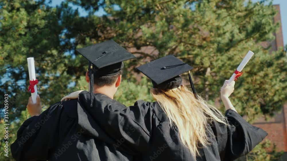 Rear view of Graduates congratulate each other on graduating from ...