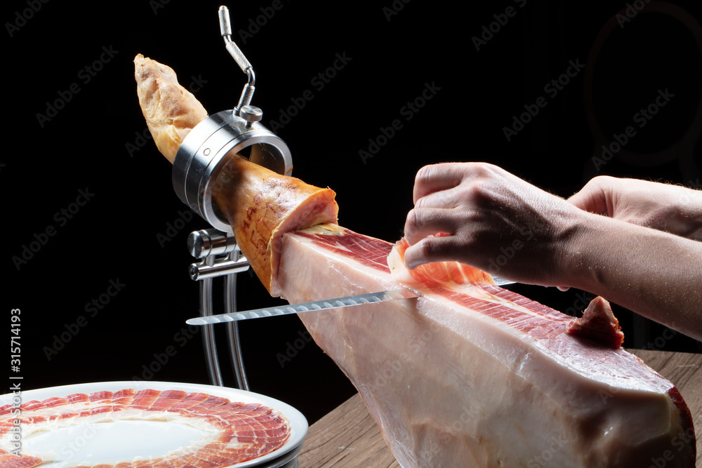corte de jamón ibérico, mano con cuchillo cortando jamón. Iberian ham ...