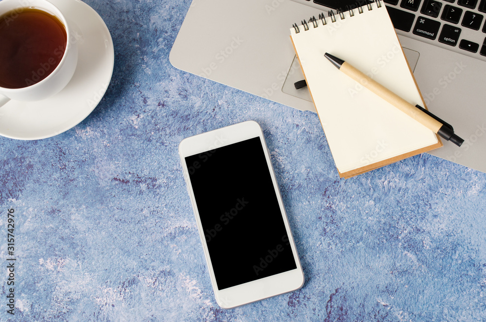 White smartphone with black blank screen on office desk with laptop ...