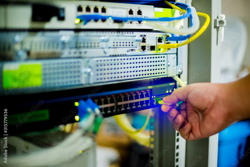 Hand holding fiber optic cord with Ethernet cables and network ...