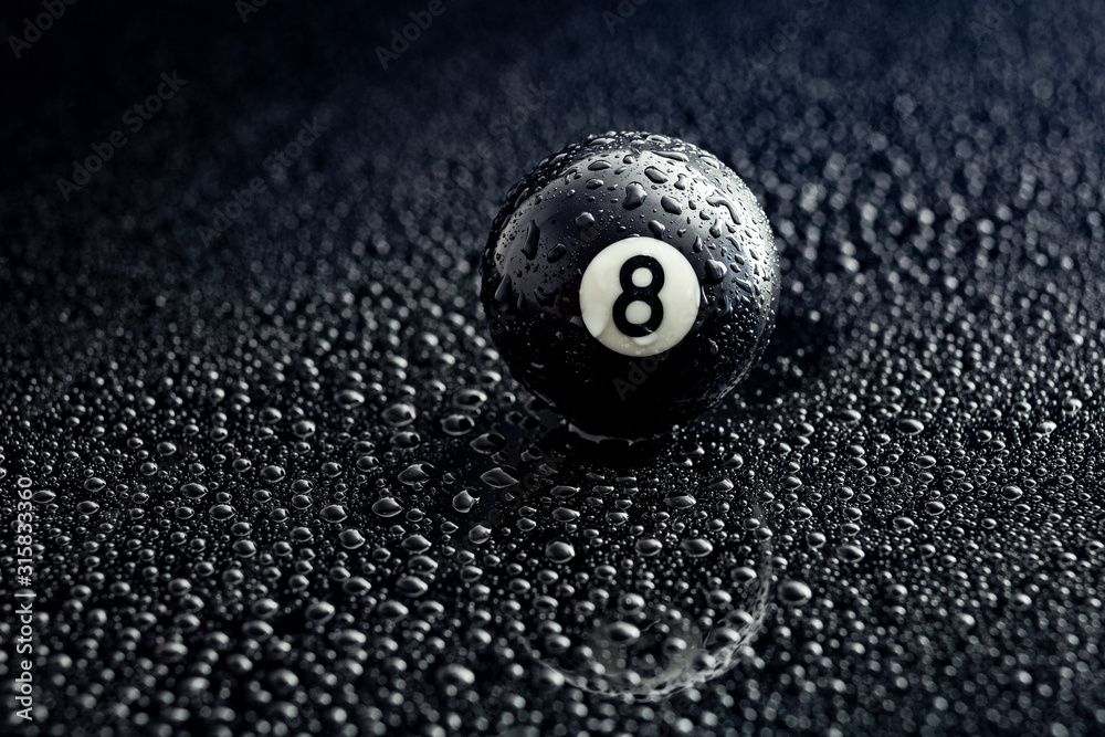 number eight billiard ball with water drops on a black background ...