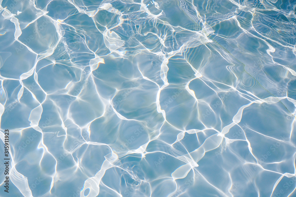 Blue water surface with bright sun light reflections, water in swimming ...