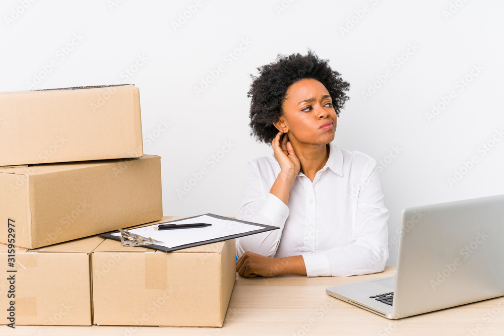 Warehouse manager sitting checking deliveries with laptop touching back ...