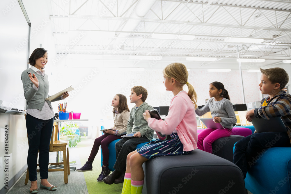 Elementary students listening to teacher in classroom Stock Photo ...