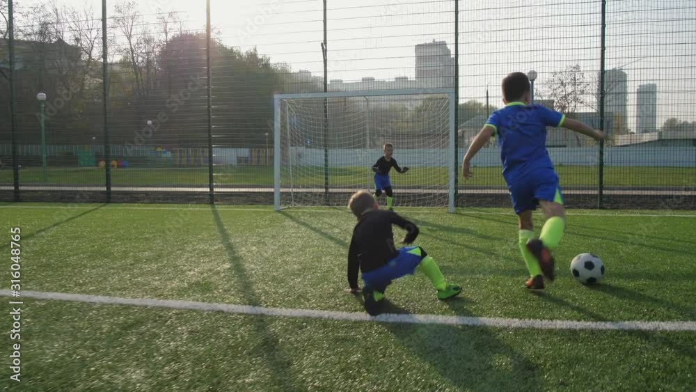 Children's soccer team playing football outdoors, forward bypassing ...