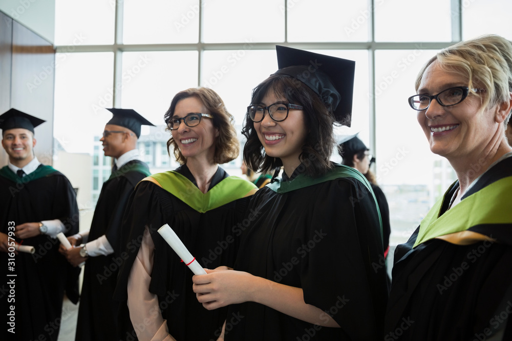 Smiling college graduate and professors cap and gown Stock Photo ...