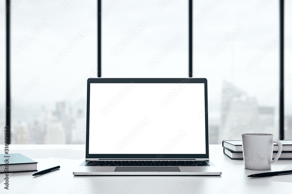 Laptop with blank white screen on a desktop on a big window background ...